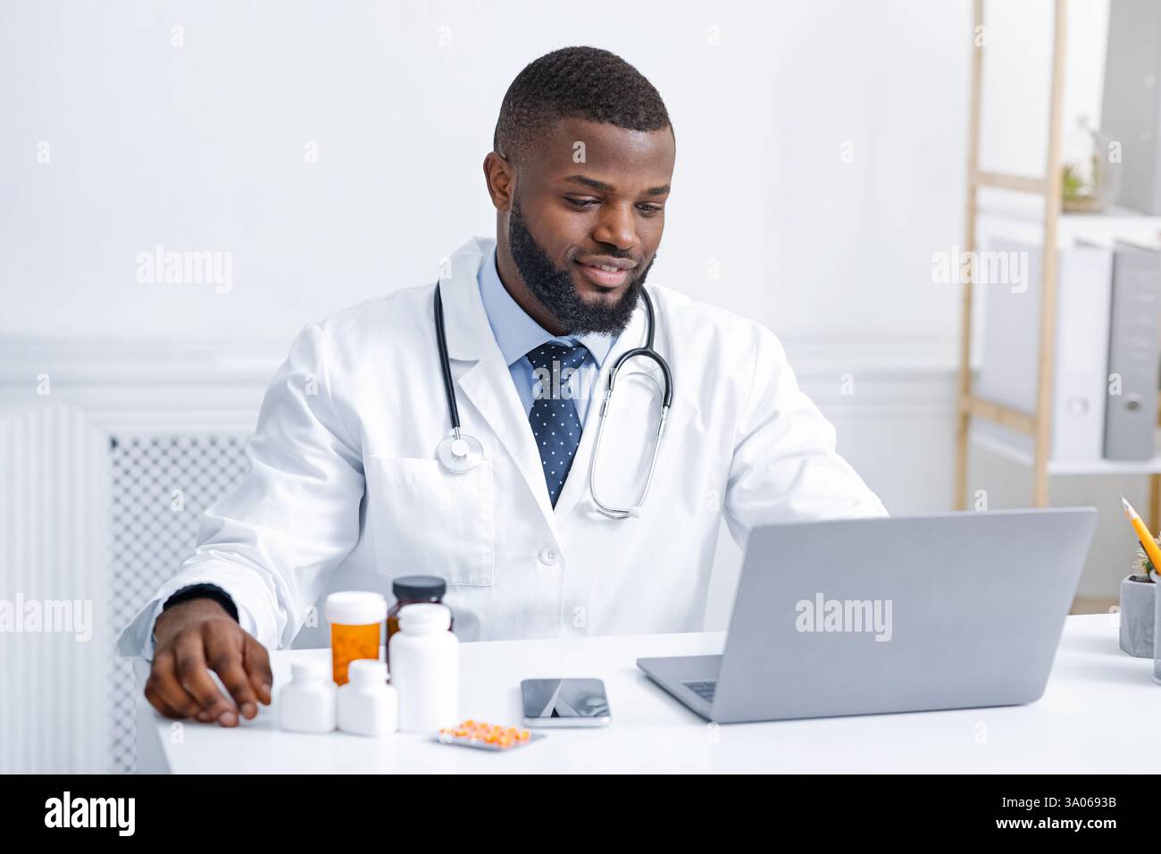 Concentrated african doctor checking on new pills Stock Photo - Alamy