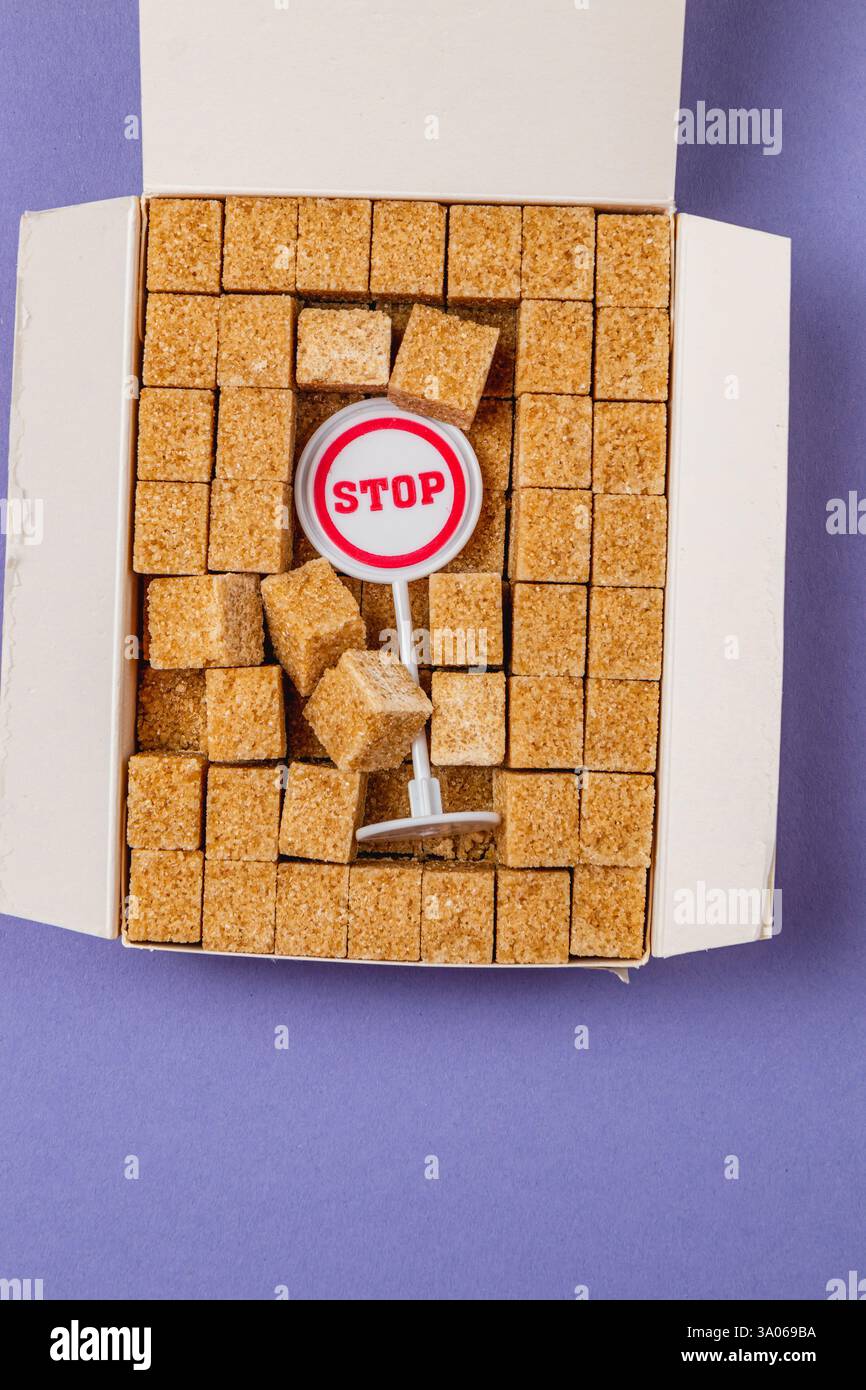 A cluster of brown sugar cubes fills a box, with a small stop sign ...