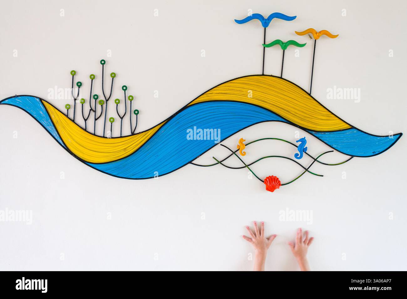 stretching hands of a child reaching a tropical installation on a white ...