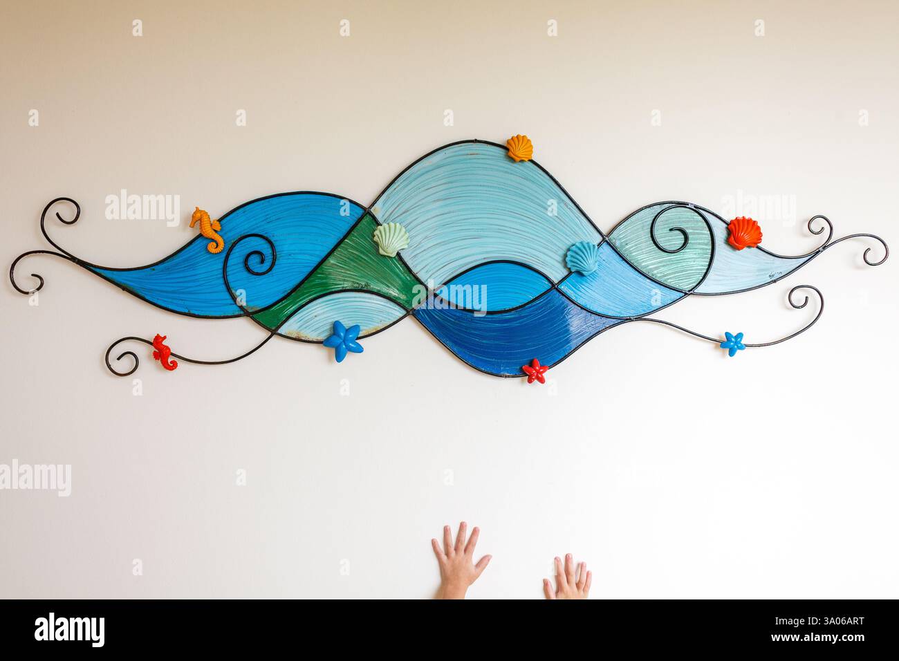 stretching hands of a child reaching a tropical installation on a white ...