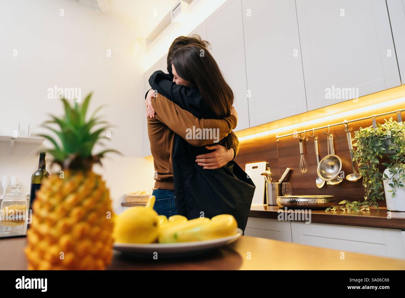 A couple shares a warm embrace in a cozy kitchen filled with fresh ...