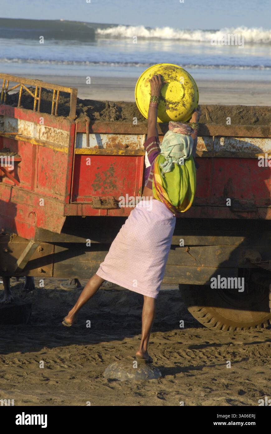 Female worker lifting sand and filling trolley at Kalamb beach, Bassein ...