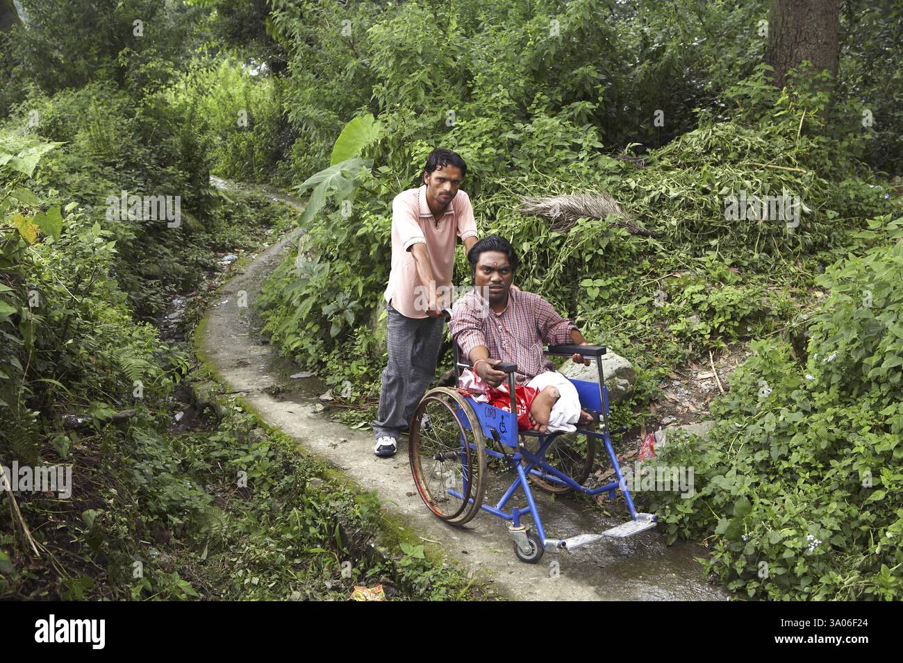 Volunteer helping handicap pushing wheelchair on walkway initiative ...