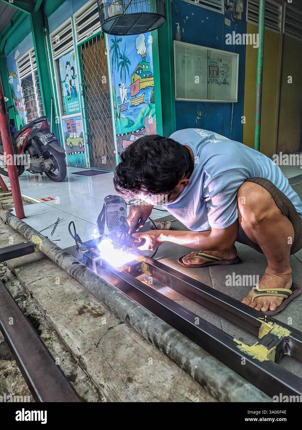 A worker skillfully welds a metal structure outside. Sparks fly as the ...