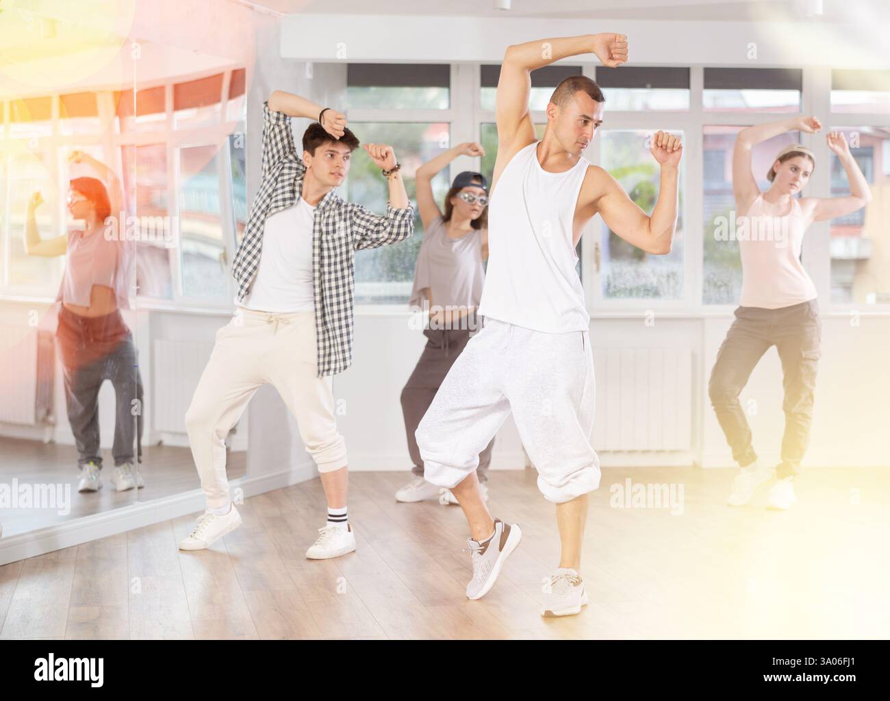 Young man standing performs basic hip hop movements in front of group ...