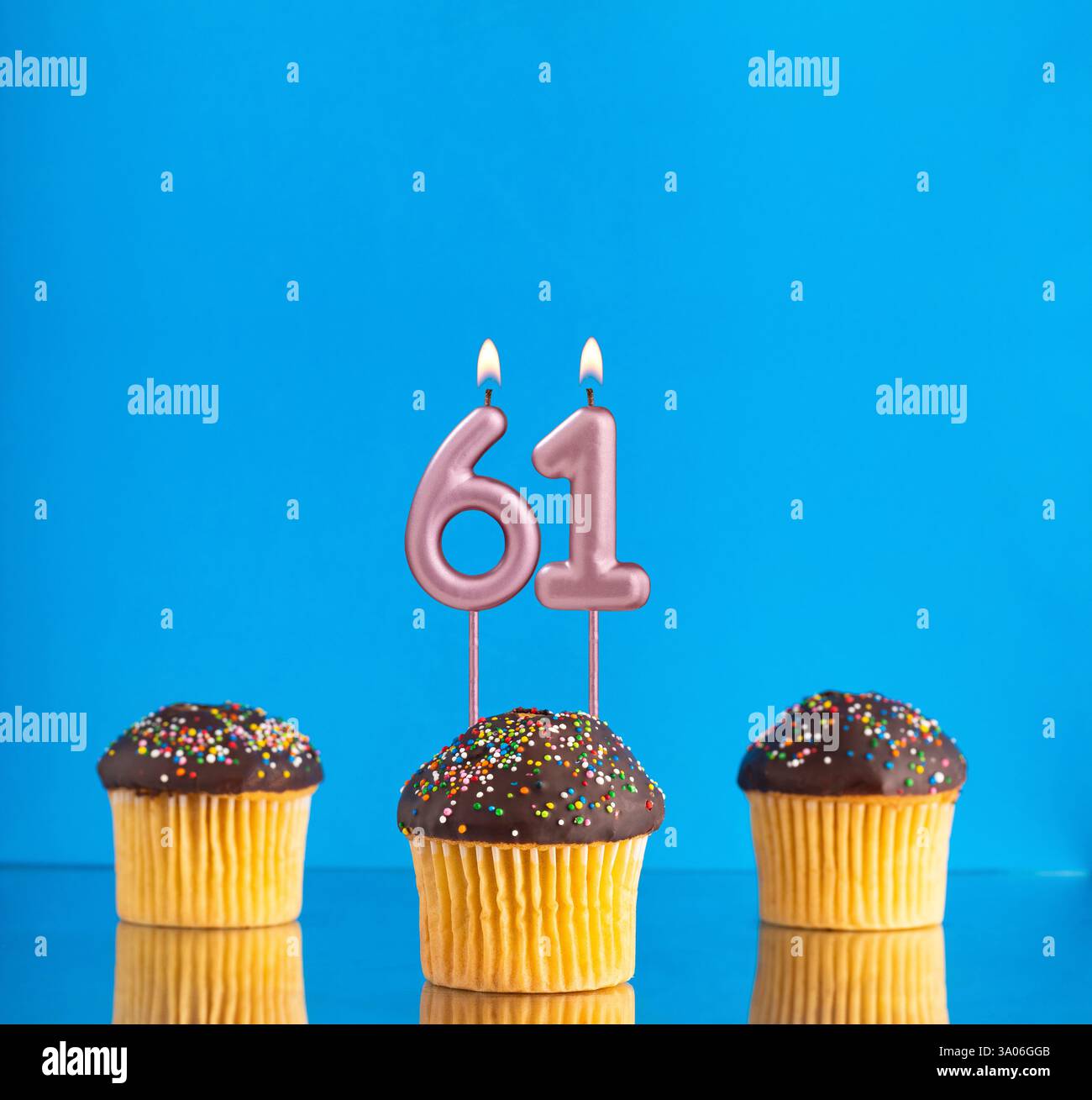 Three birthday cupcakes with number 61 candle - Blue background Stock ...