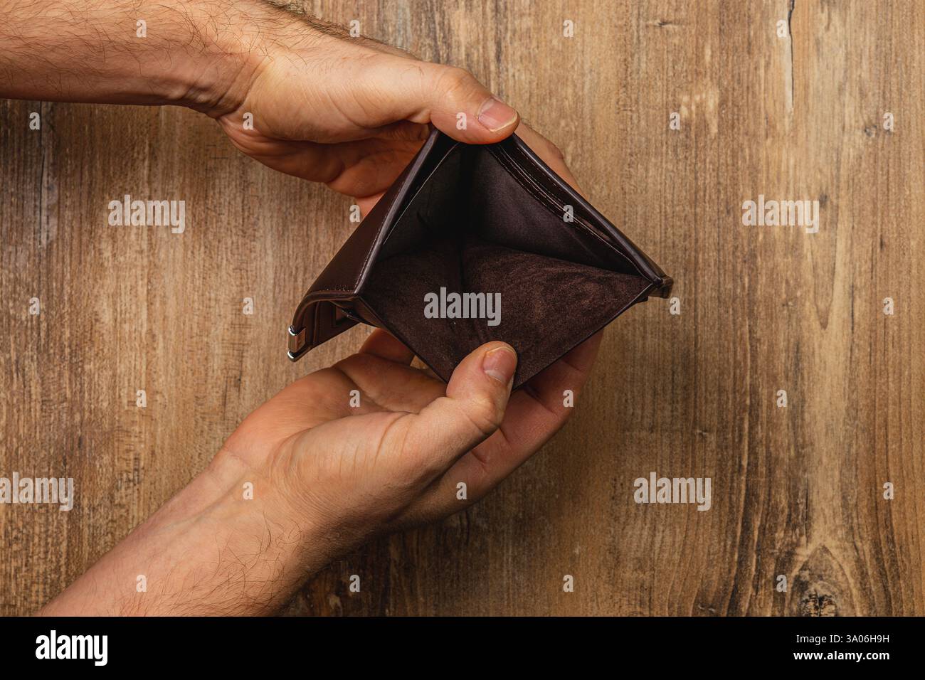 A male businessman examines his empty leather wallet, reflecting on his ...
