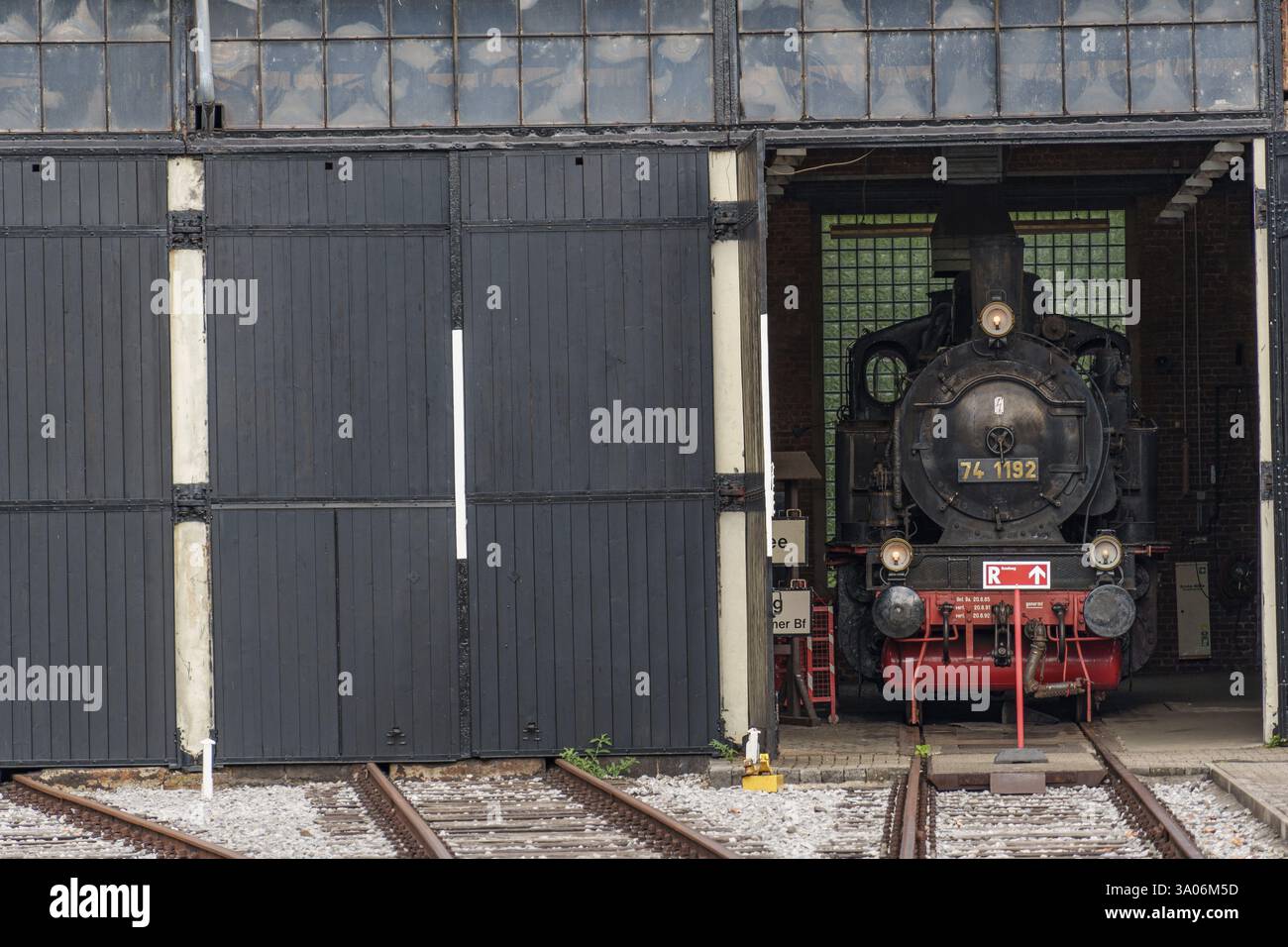 Historic black steam locomotive stands on the rails in an open roundhouse, bochum, westphalia ...