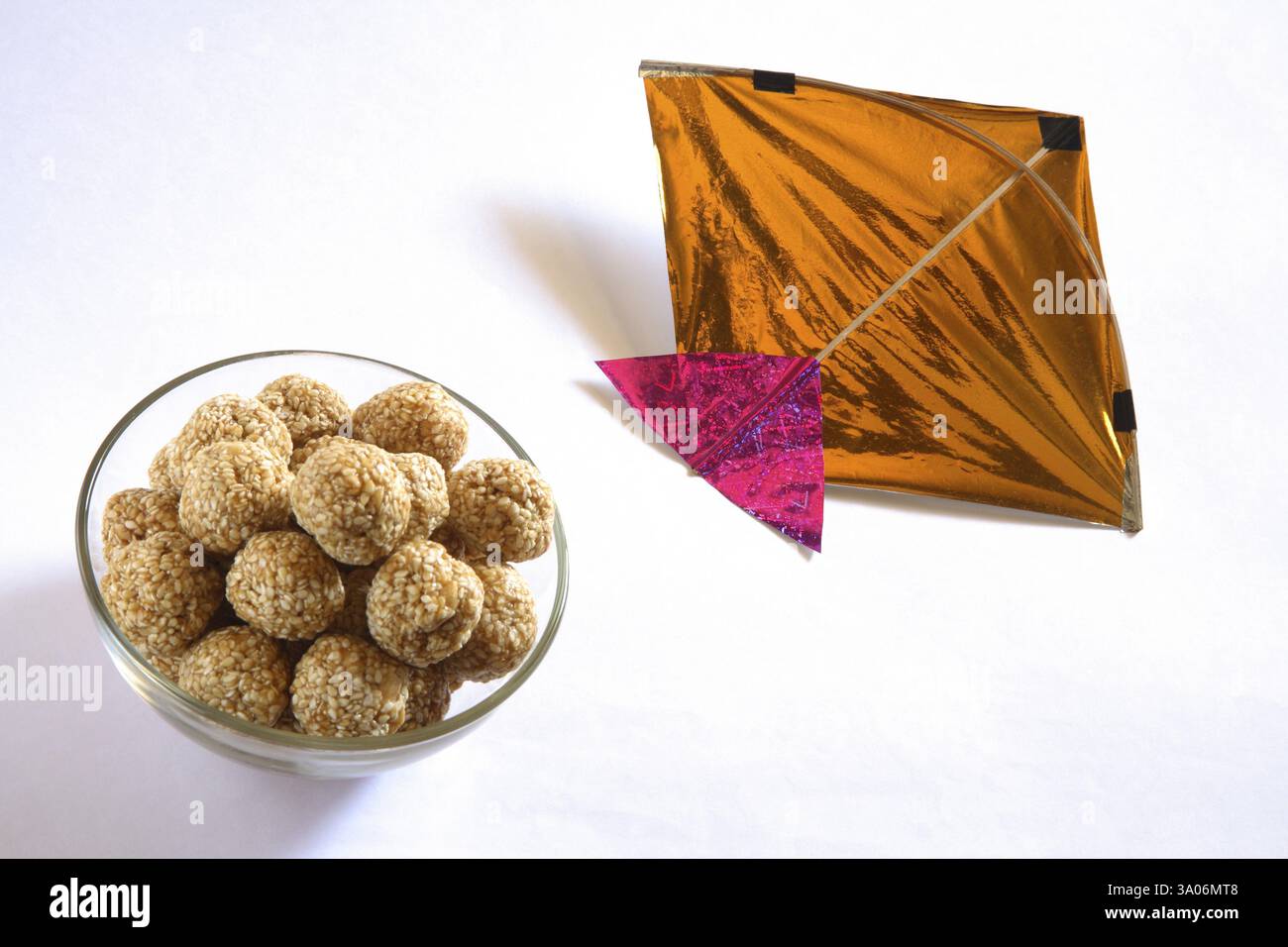 Sweet tilgur or til gul sesame laddoos in bowl with kite on white ...