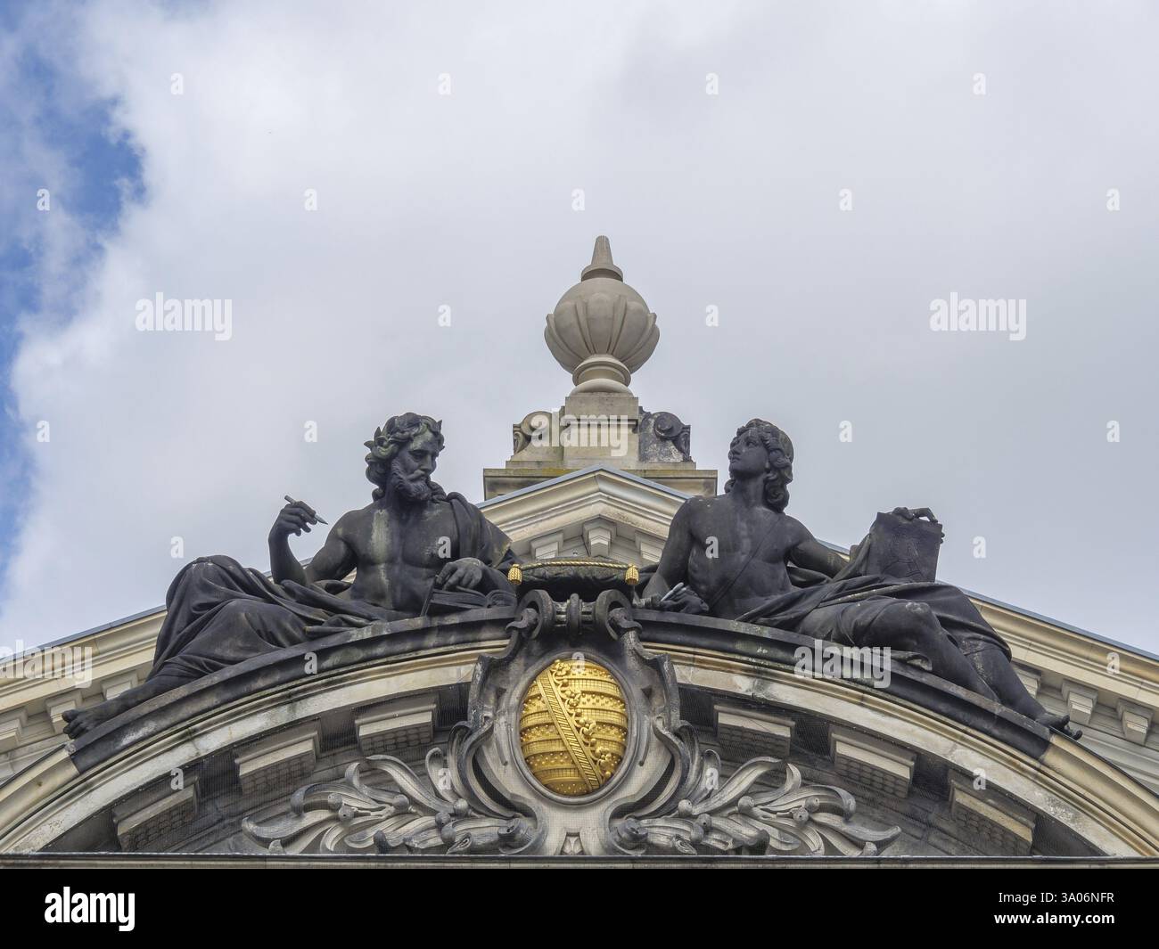 Sculptures on a roof gable with golden decoration under a blue sky ...