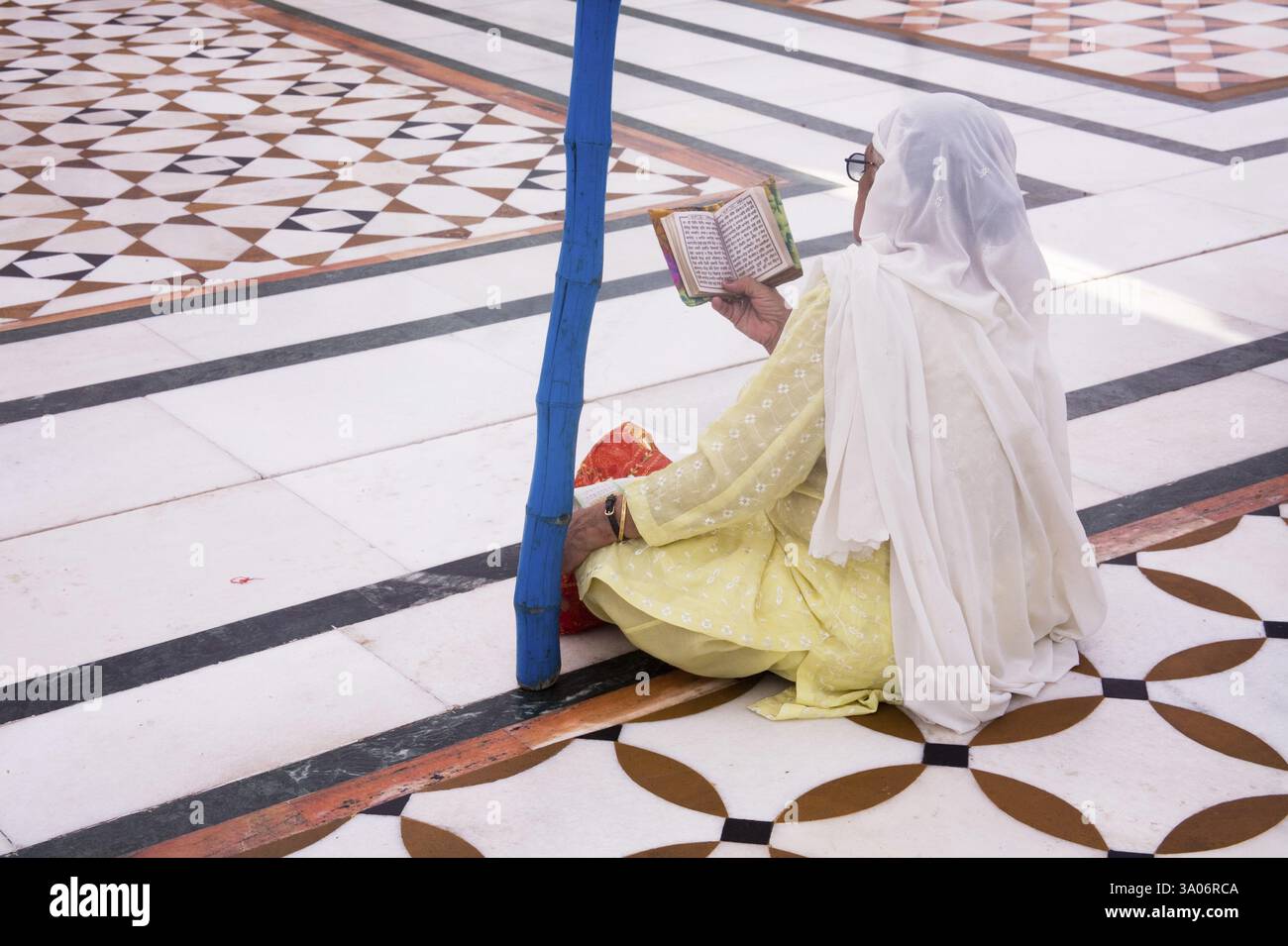 Sikh woman praying sitting on the floral structure pattern of the white ...