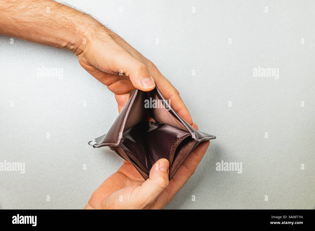 A businessman examines his empty wallet with a look of despair. This ...
