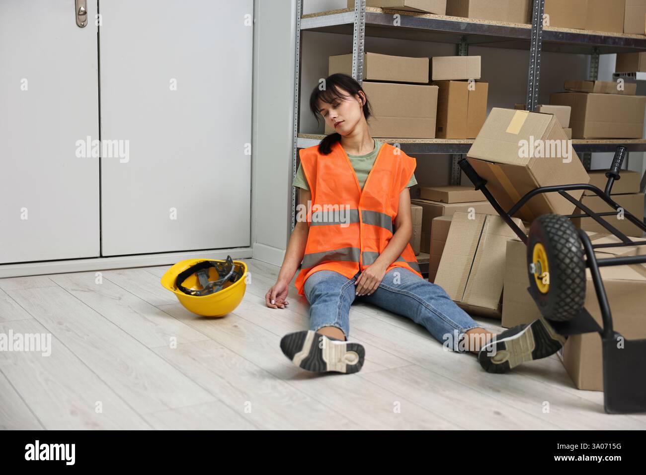 Accident at work. Unconscious woman and overturned hand truck on floor ...