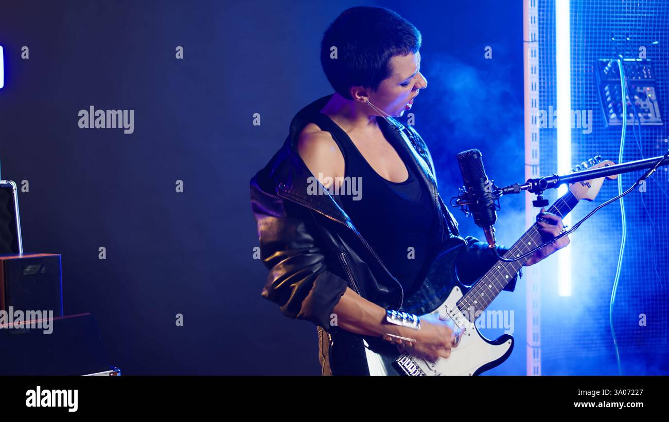 Rock star woman in a leather jacket playing a heavy metal set ...