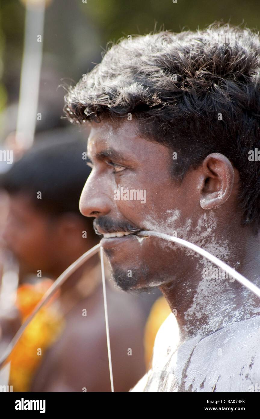 Man piercing spike through cheeks discharging vow in Thaipusam festival ...