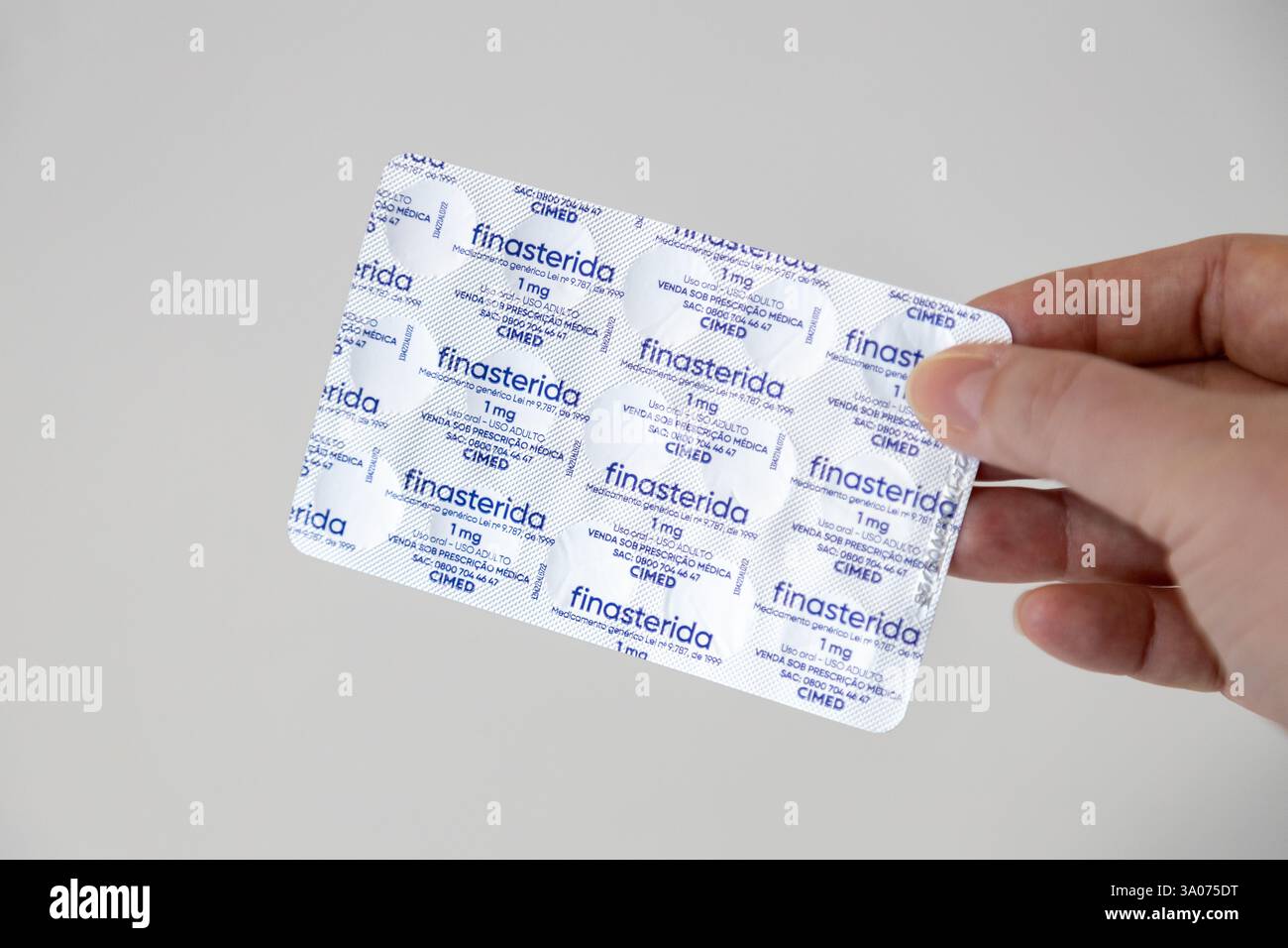 Hand holding a blister pack of Finasteride 1mg, a generic medication ...