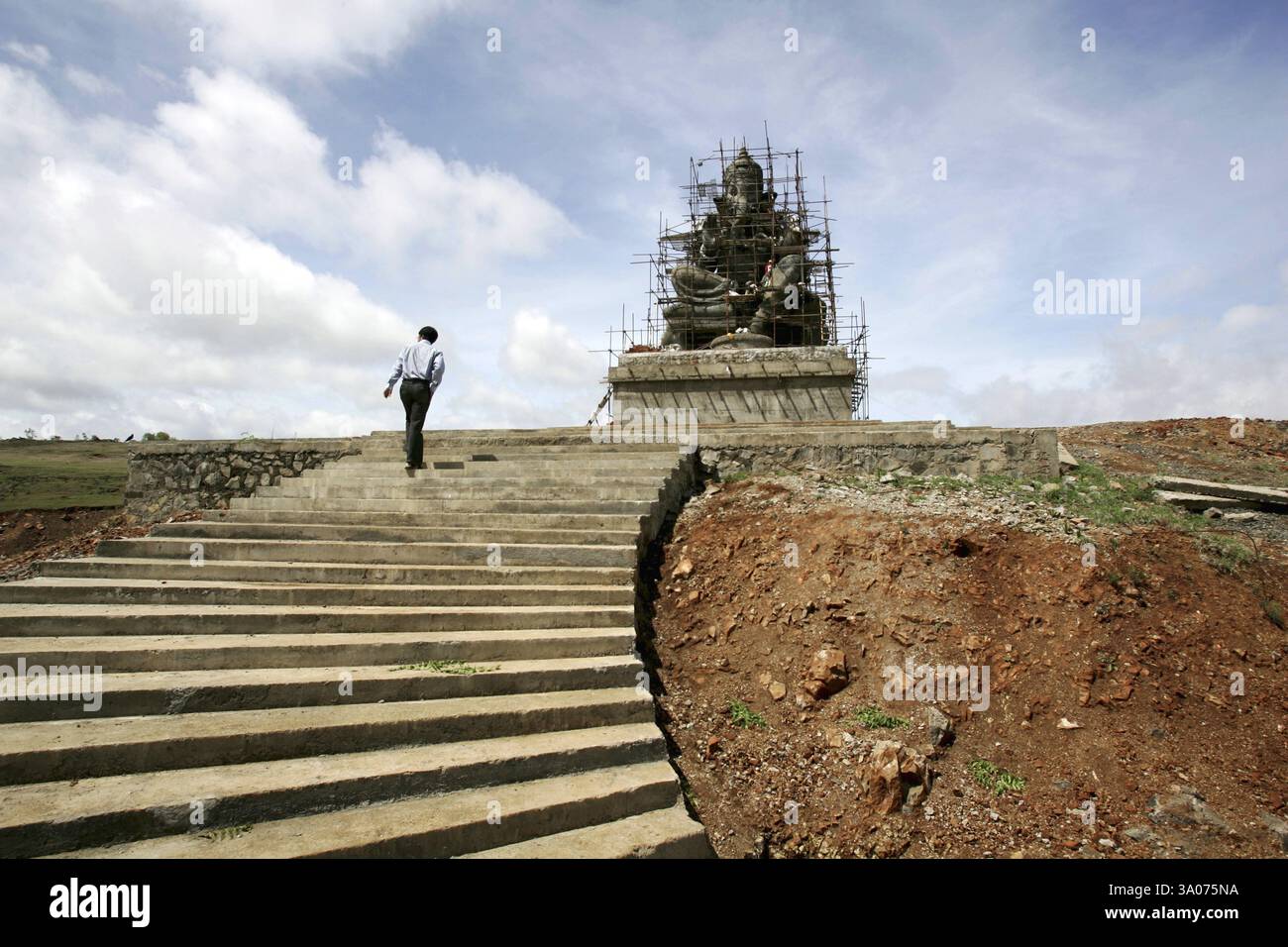 Man walking on stairs leading to huge statue of lord Ganesha elephant ...