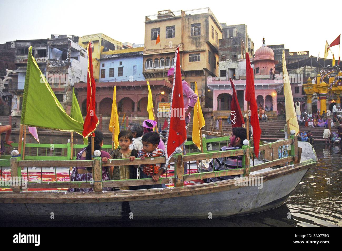 Pilgrims in boat in front of colorful temples on banks of Yamuna river ...