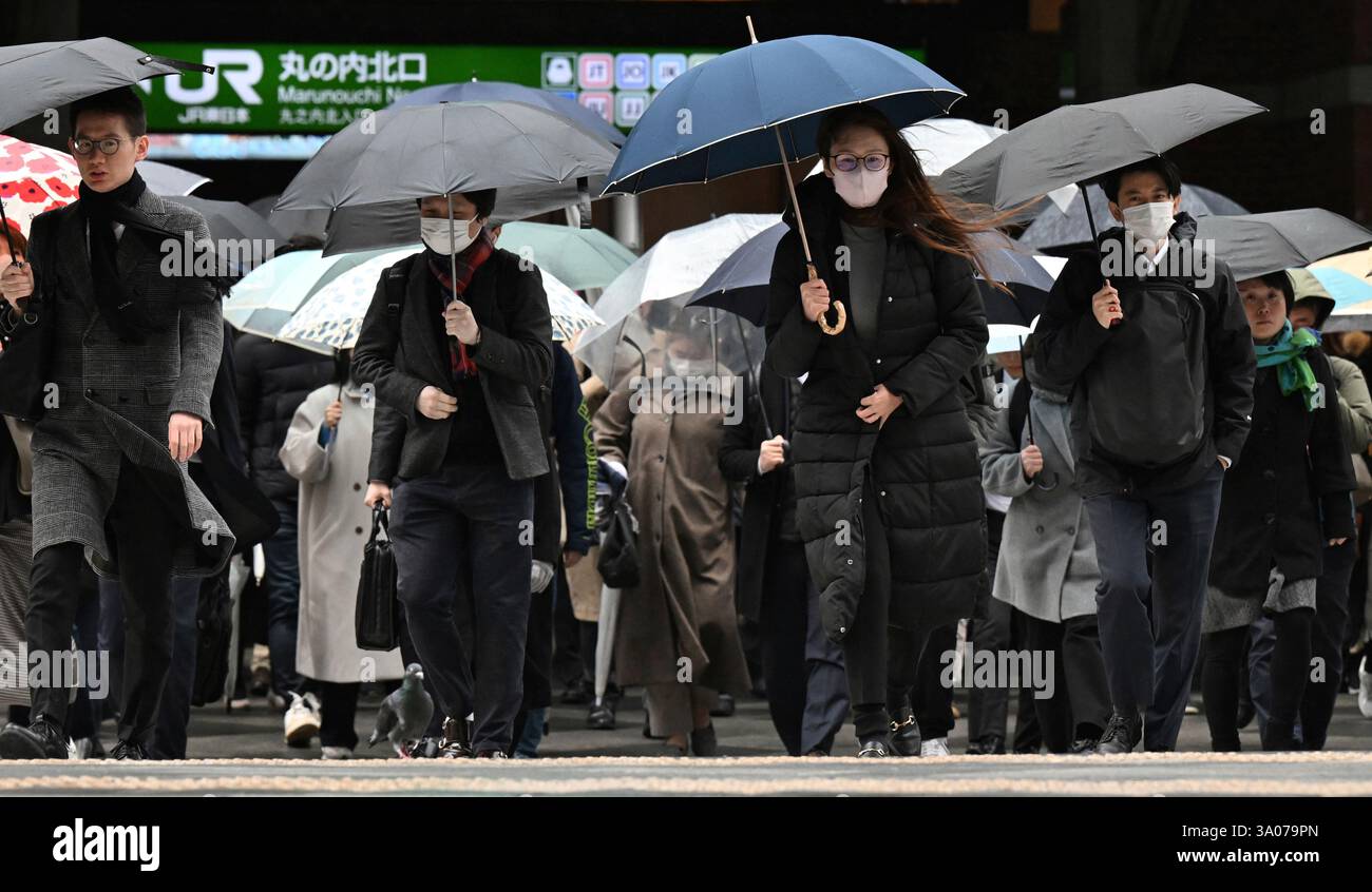 Commuters and others walk in the cold rain in near Tokyo Station in ...