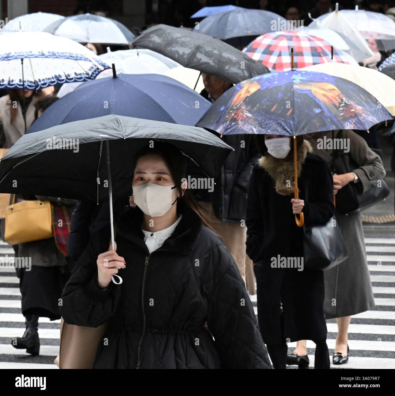 Commuters and others walk in the cold rain in near Tokyo Station in ...