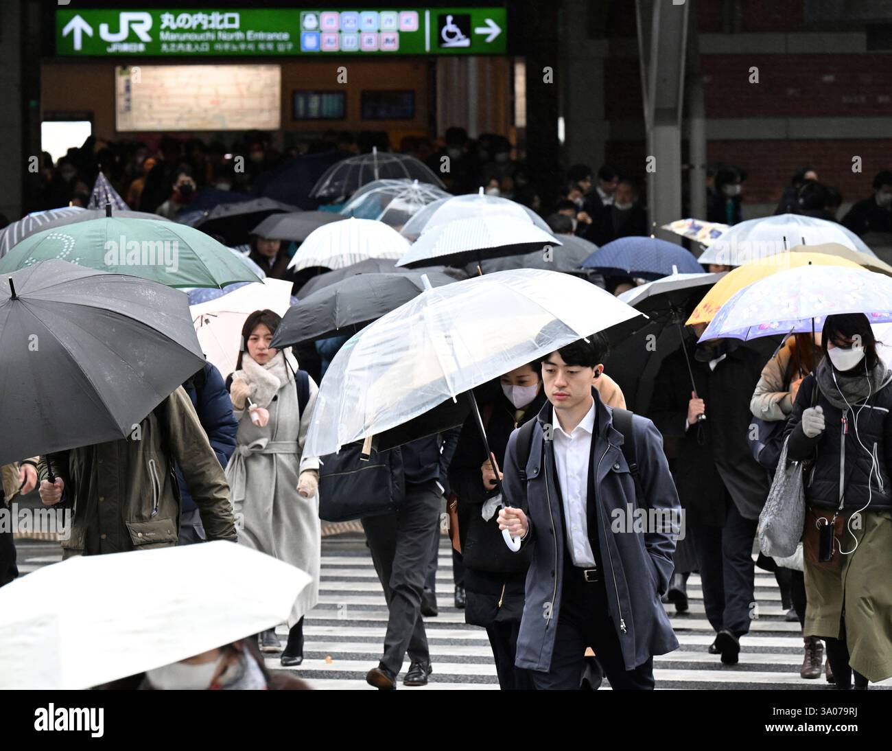 Commuters and others walk in the cold rain in near Tokyo Station in ...