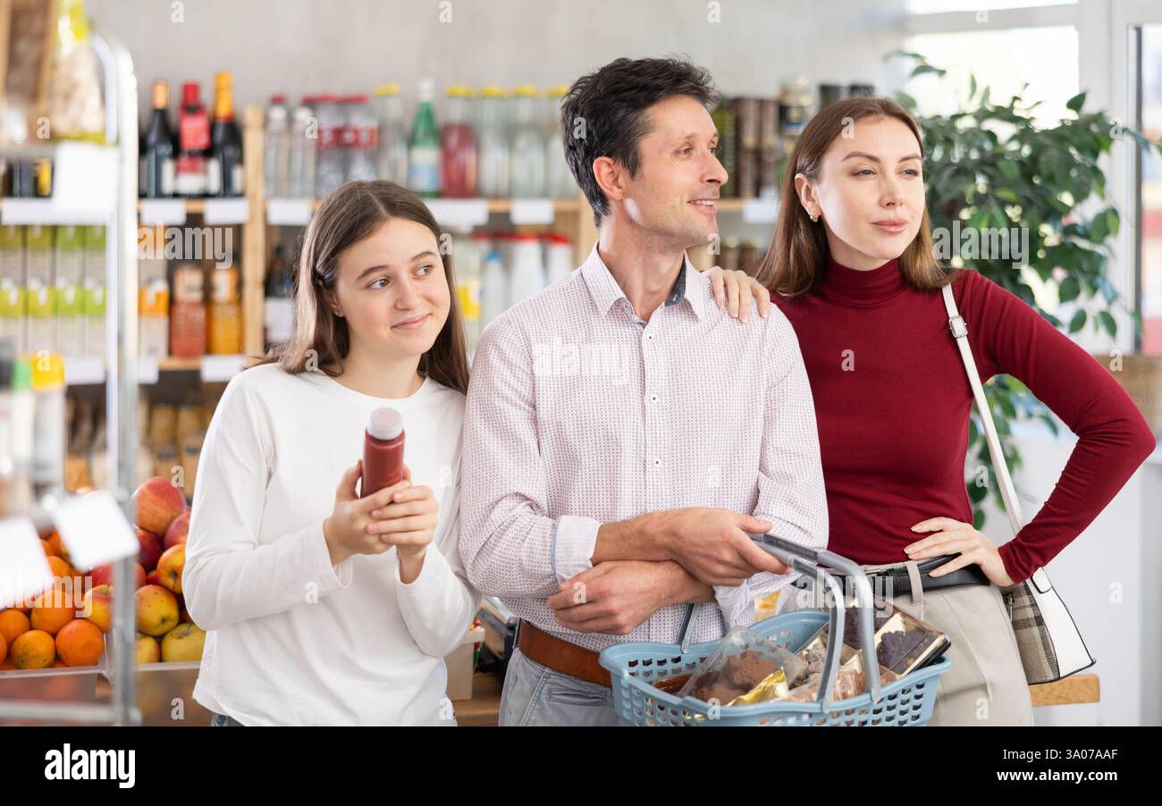 In store, family with purchases in hands looking for something on shelf ...