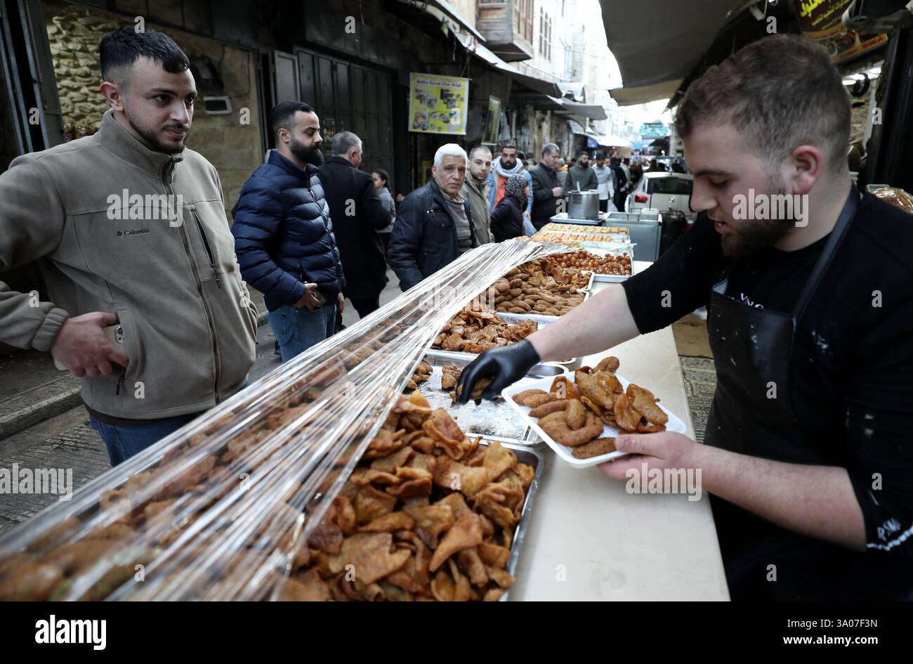 Nablus. 2nd Mar, 2025. A man sells traditional sweets at a market ...