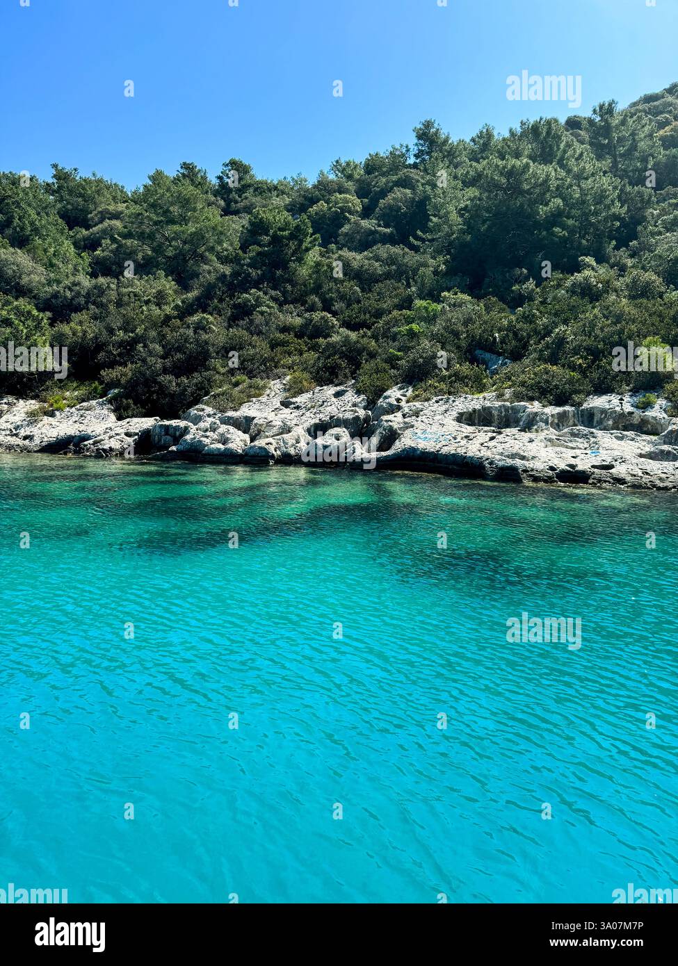The vibrant turquoise waters reflect the blue sky while a rocky ...
