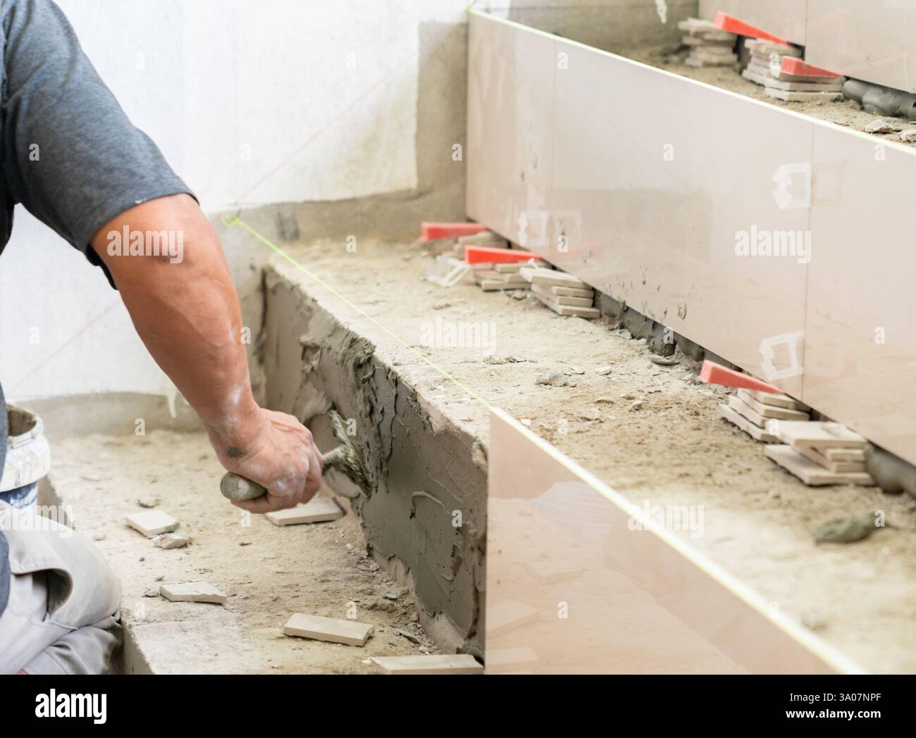 Worker tiling stairs, applying adhesive on step. Process of ...