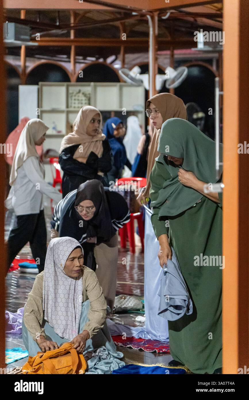 A close-up from the door of Muslim women dressing themselves before ...