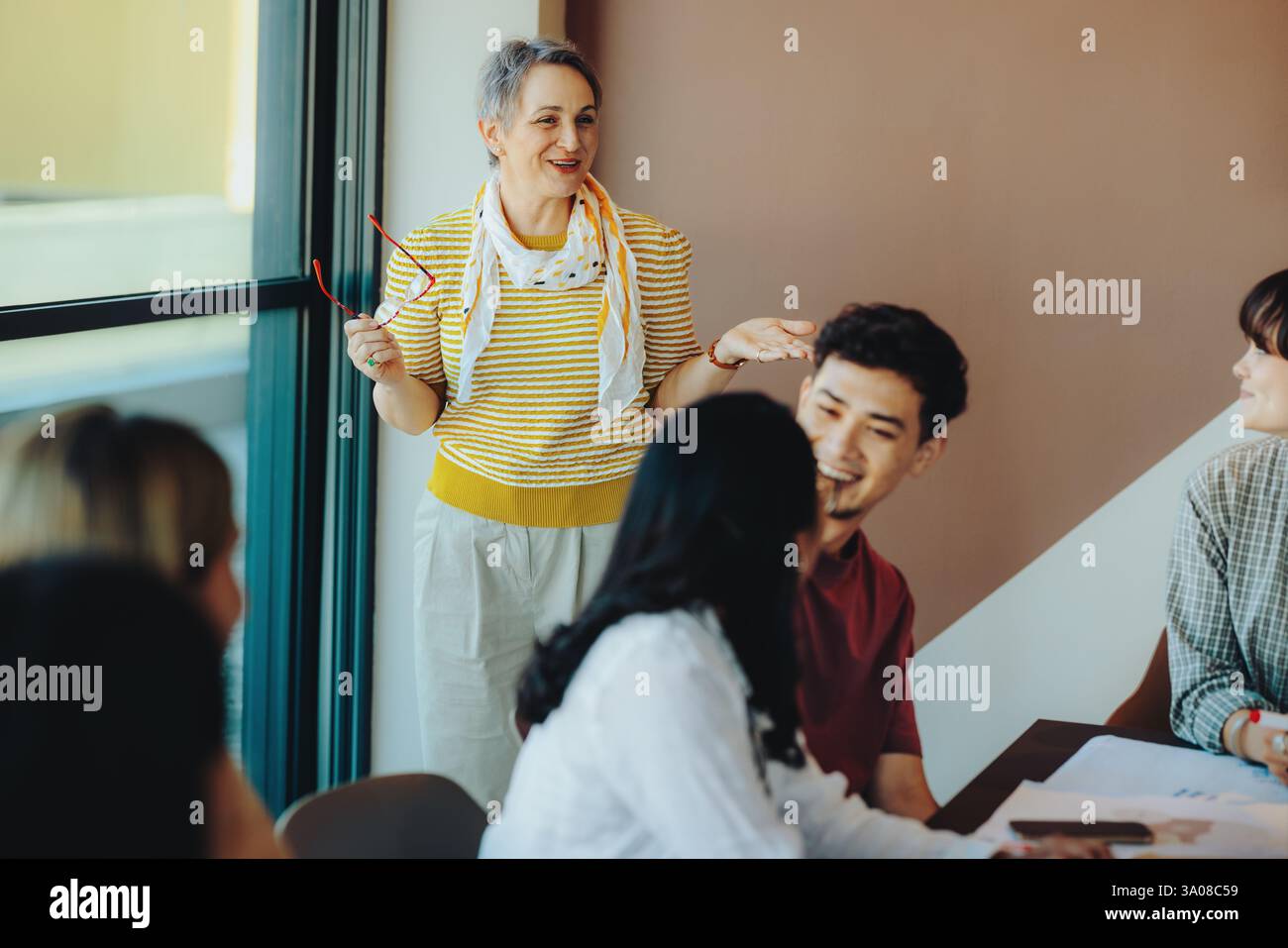A joyful high school teacher interacts with students during an engaging ...