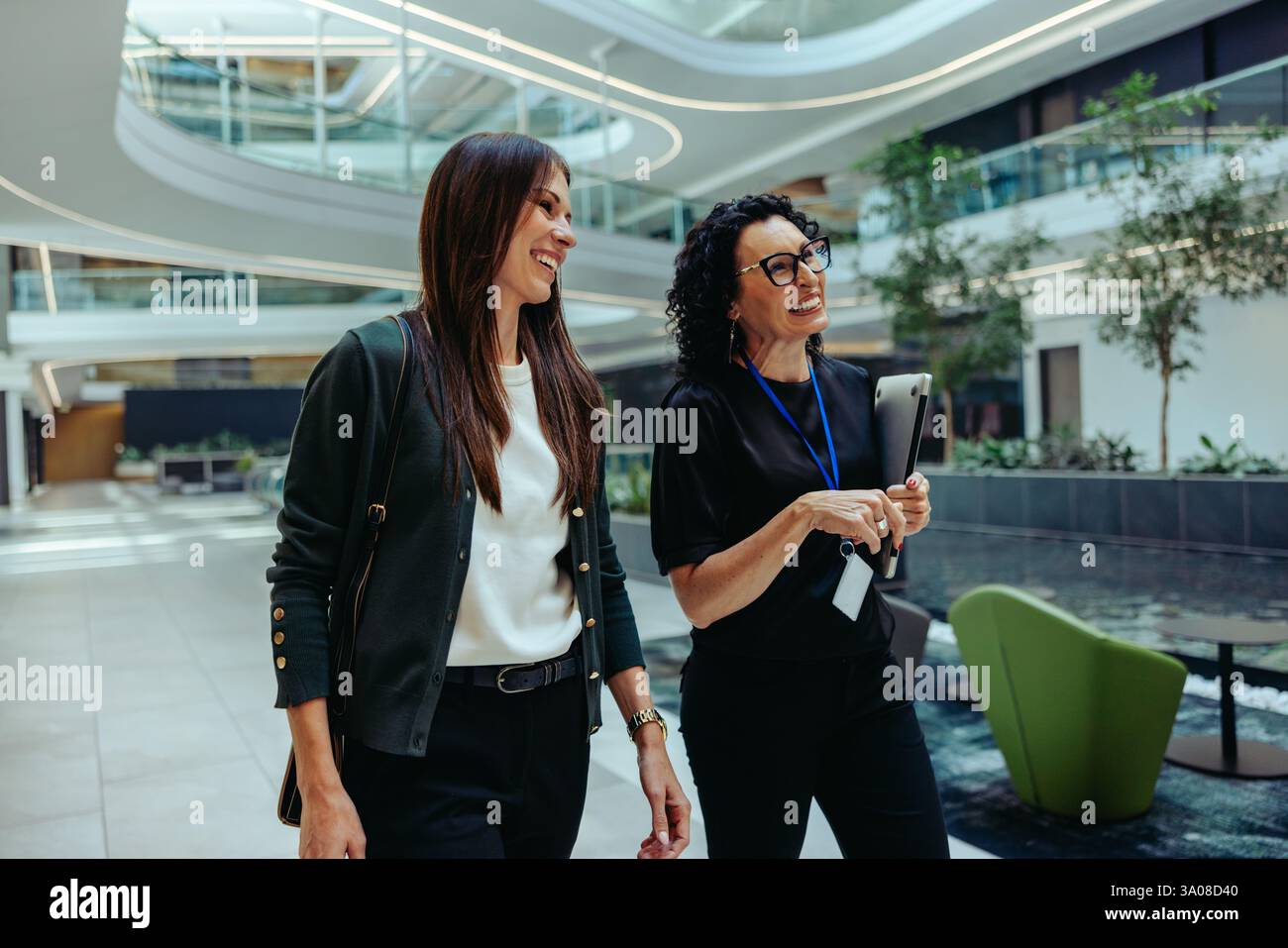 Two female coworkers walk through a bright, modern office space ...