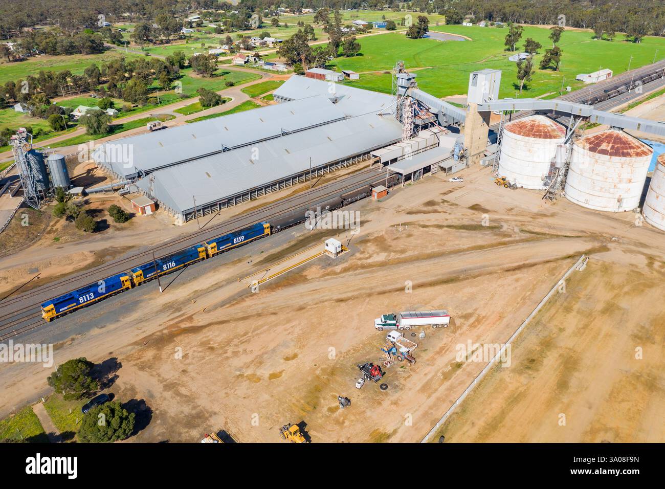 Aerial view of a long train at a rural station with grain silos at ...