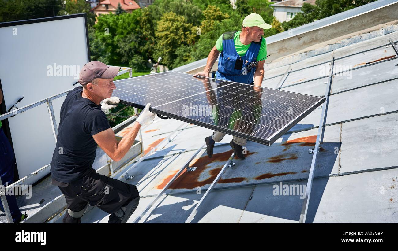 Workers building solar panel system on metal rooftop of house with ...