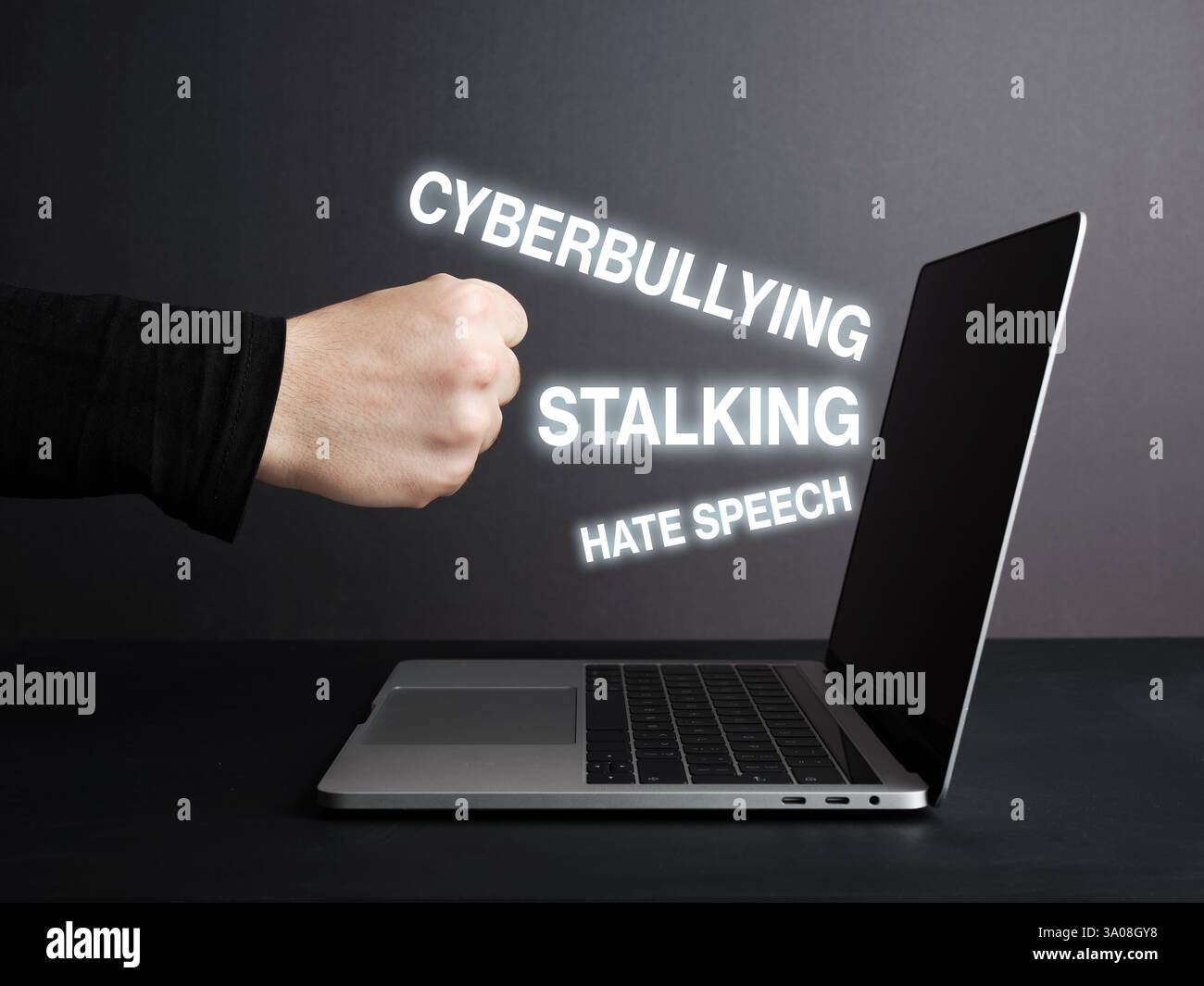 Fist hitting laptop with cyberbullying, stalking and hate speech texts ...