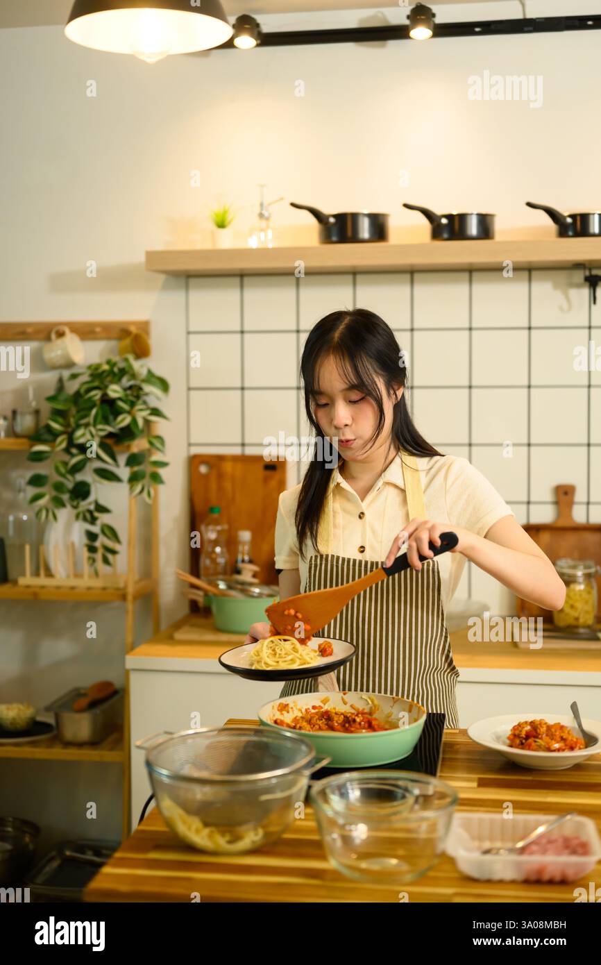 Asian woman stirring rich tomato based sauce on the stove while getting ...