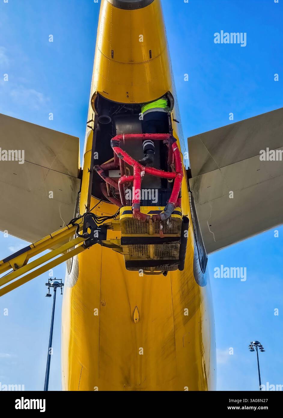 Aircraft maintenance work under the yellow fuselage with hydraulic lift ...