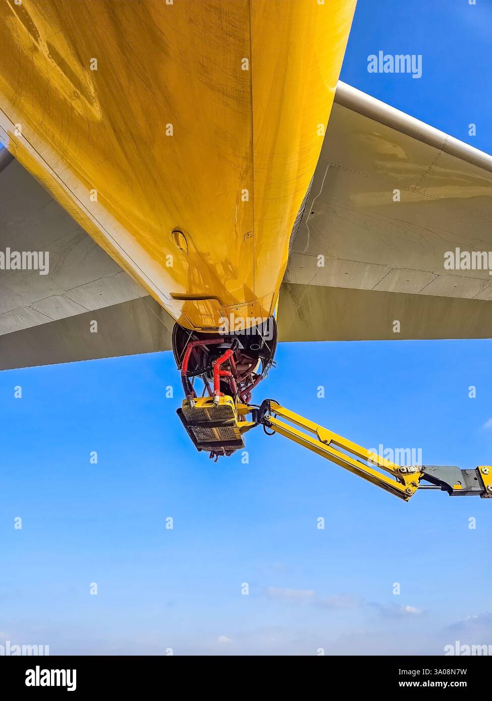 Aircraft maintenance work under the yellow fuselage with hydraulic lift ...