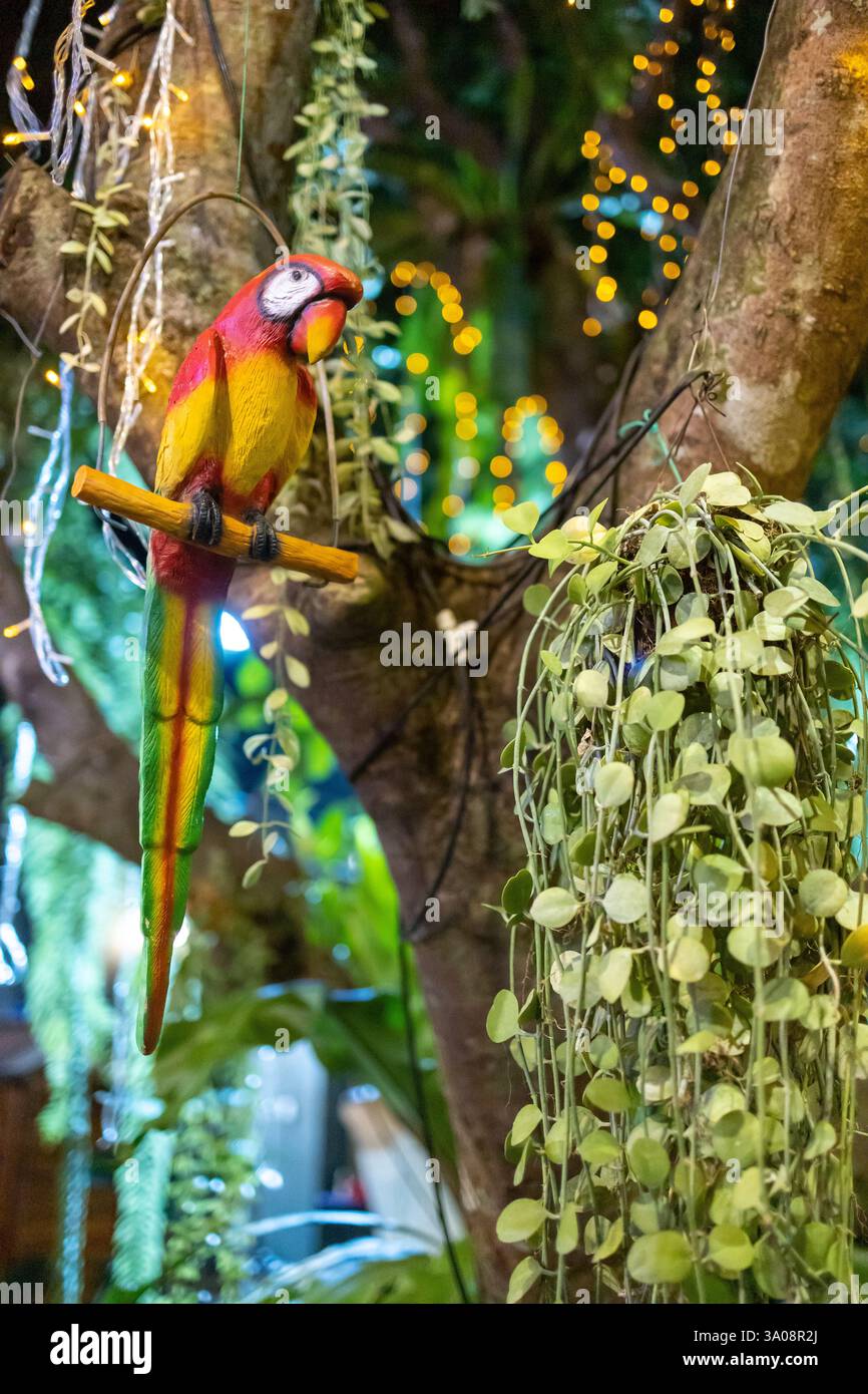 A statue macaw parrot perched on a branch, enjoying a piece of fruit ...