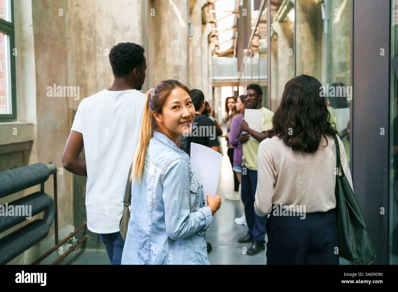 Portrait of smiling female student looking back while walking with ...