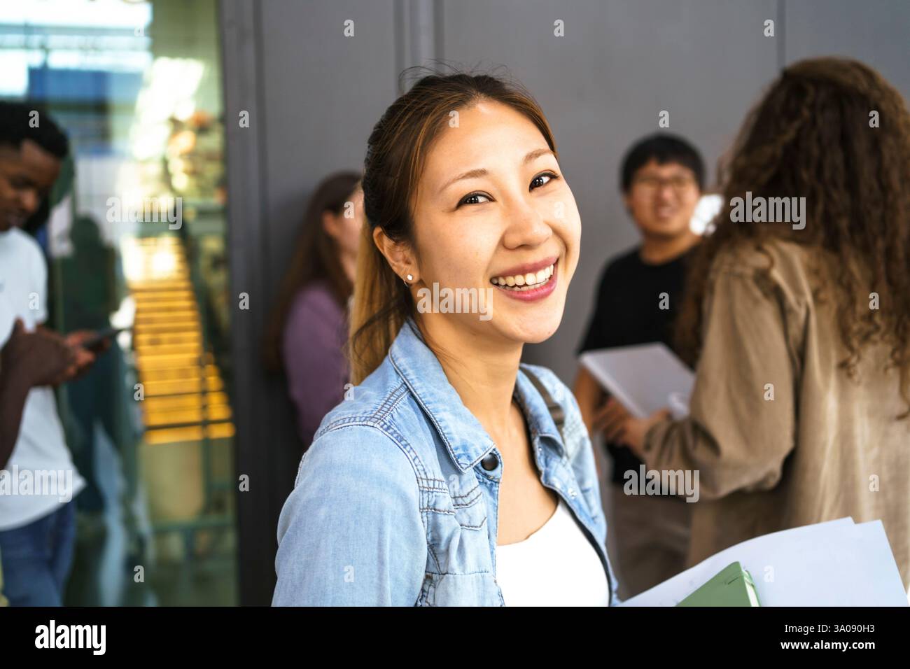 Portrait of cheerful female student with assignment papers at college ...