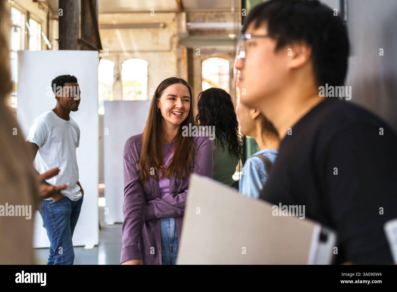 Happy female student discussing with friend while standing in college ...