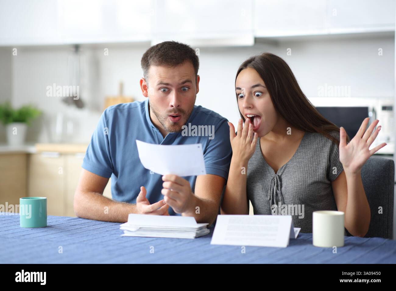 Amazed couple checking bank statement in the kitchen at home Stock ...