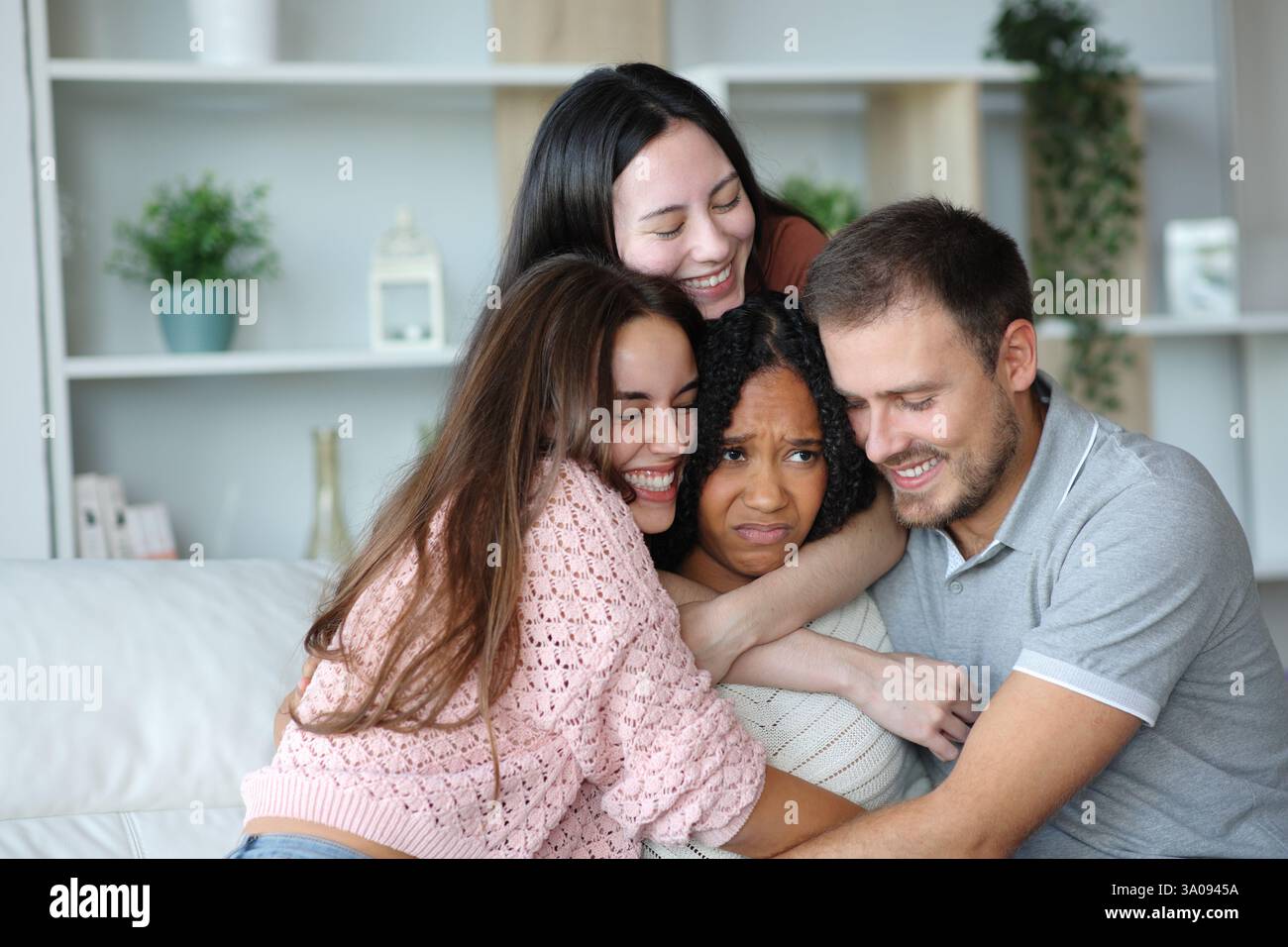 Disgusted woman being hugged by friends sitting on a couch at home ...