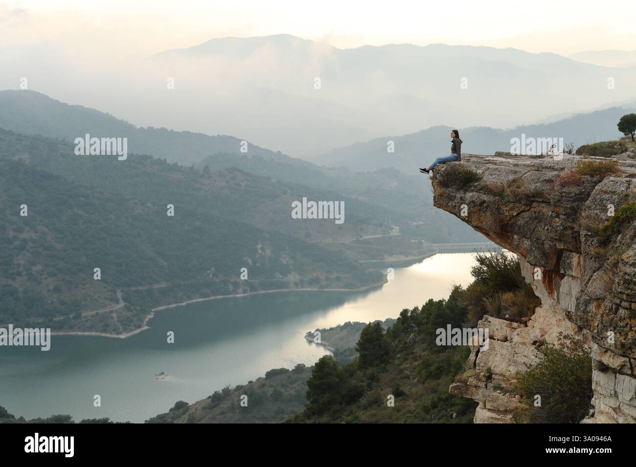 Single woman sitting in a cliff contemplating nature Stock Photo - Alamy