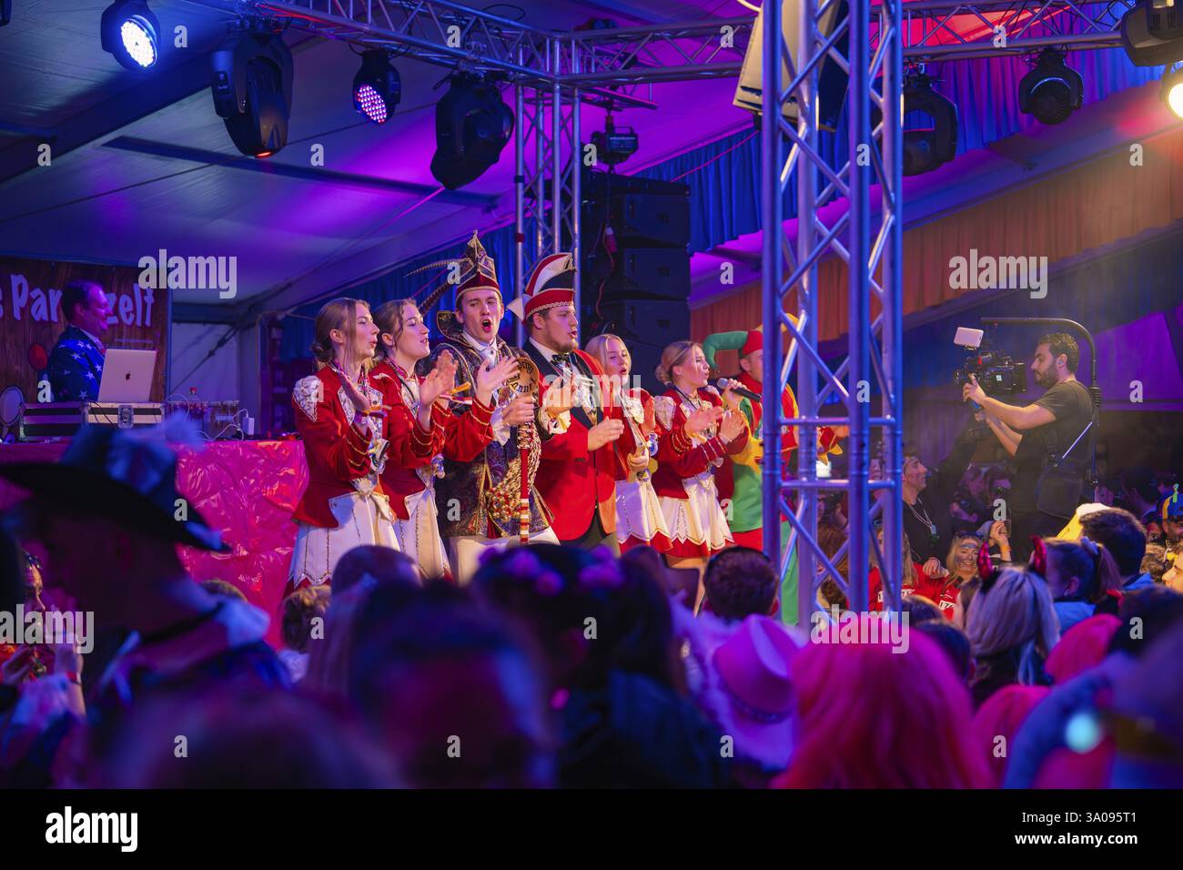 A group on stage at a carnival event, surrounded by a celebrating crowd ...