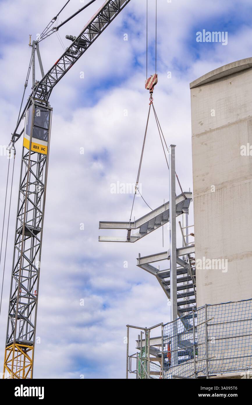 Crane lifts parts of a steel structure next to scaffolding on the ...
