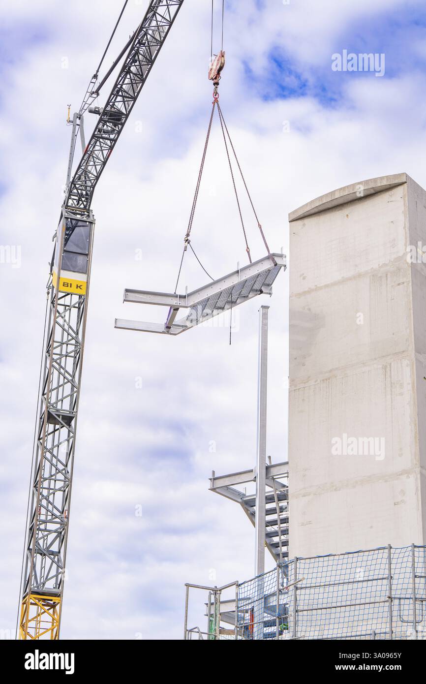 Crane lifts a steel girder on the construction site in front of a blue ...