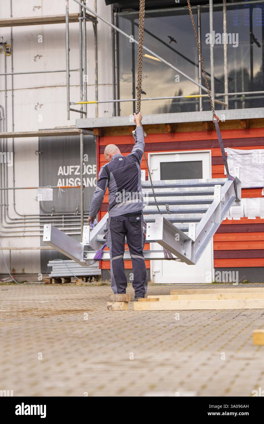 Worker with a crane moving steel girders on a construction site, Wend ...