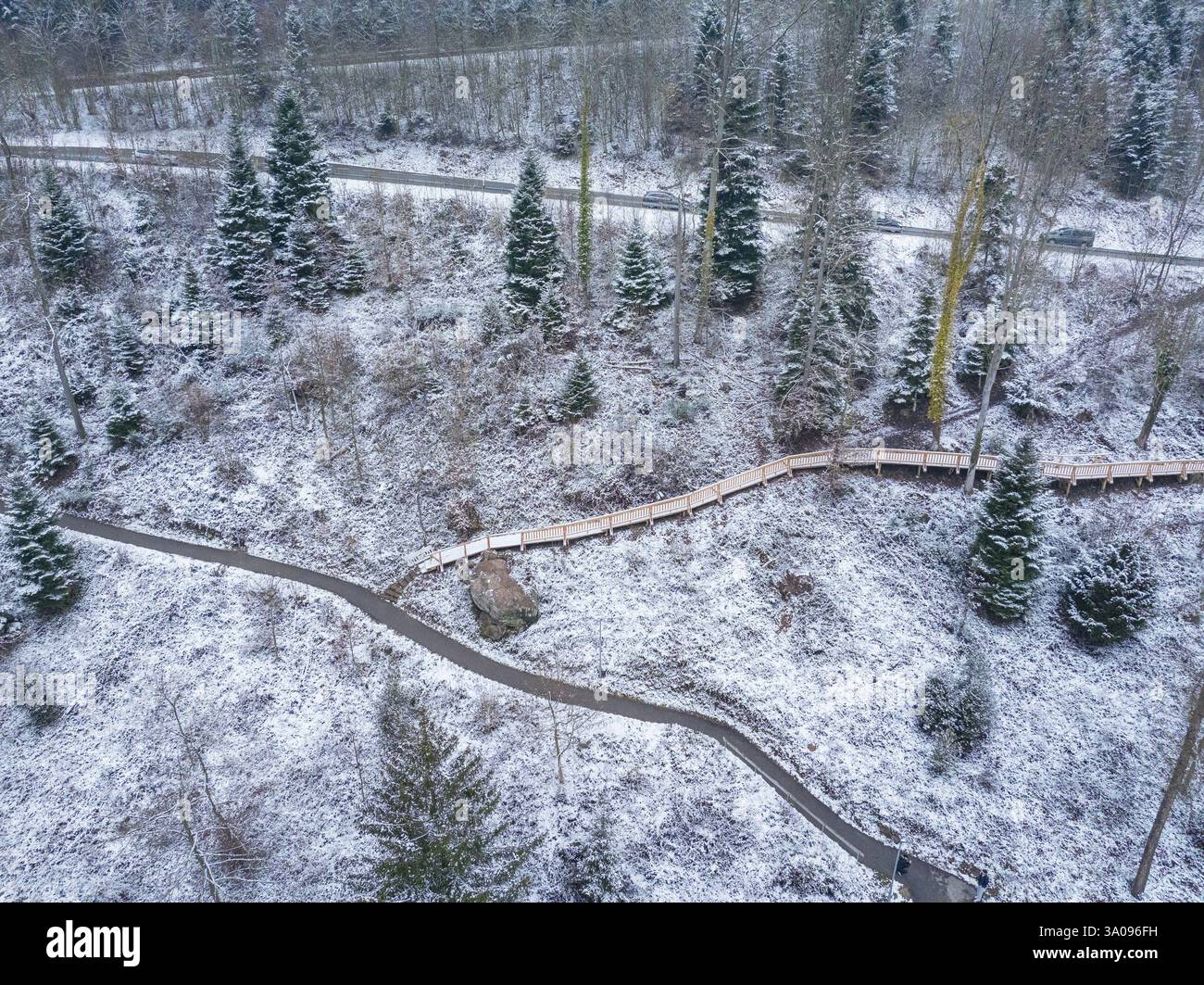Snow-covered forest landscape with winding wooden path and road, New ...